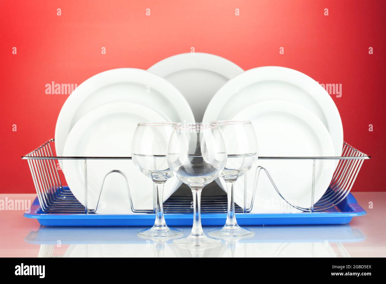 clean dishes on stand on red background Stock Photo - Alamy