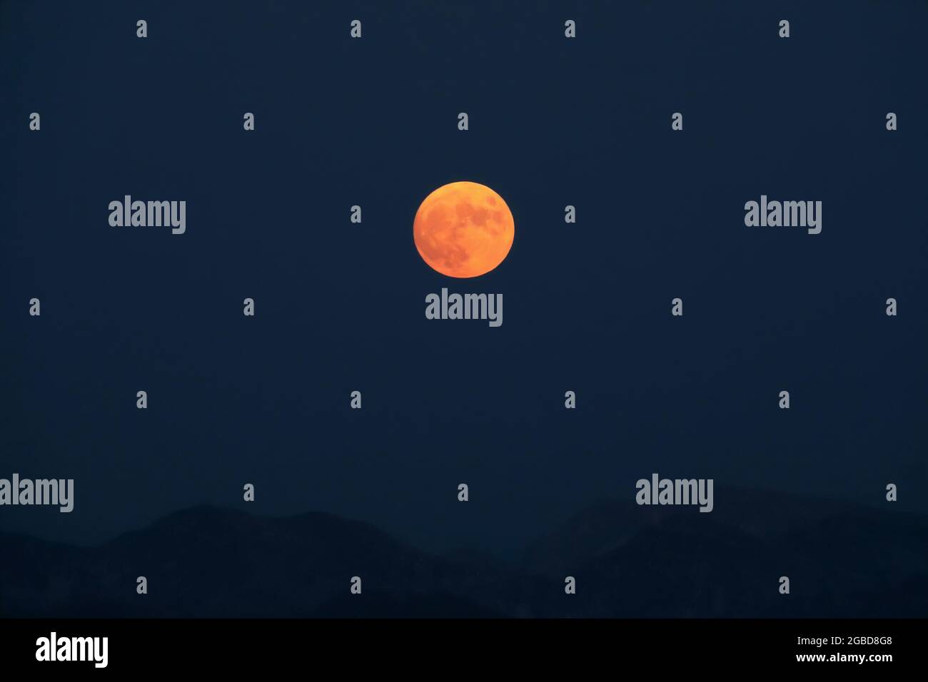 Splendid full red moon rises over the mountain ridges of the Apennines ...