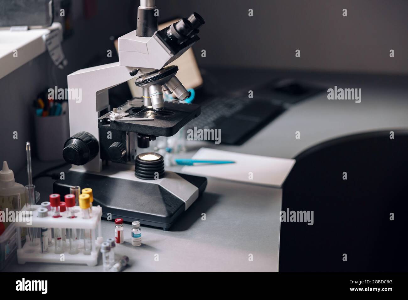 Microscope, rack with test tubes and vials on table in laboratory Stock ...