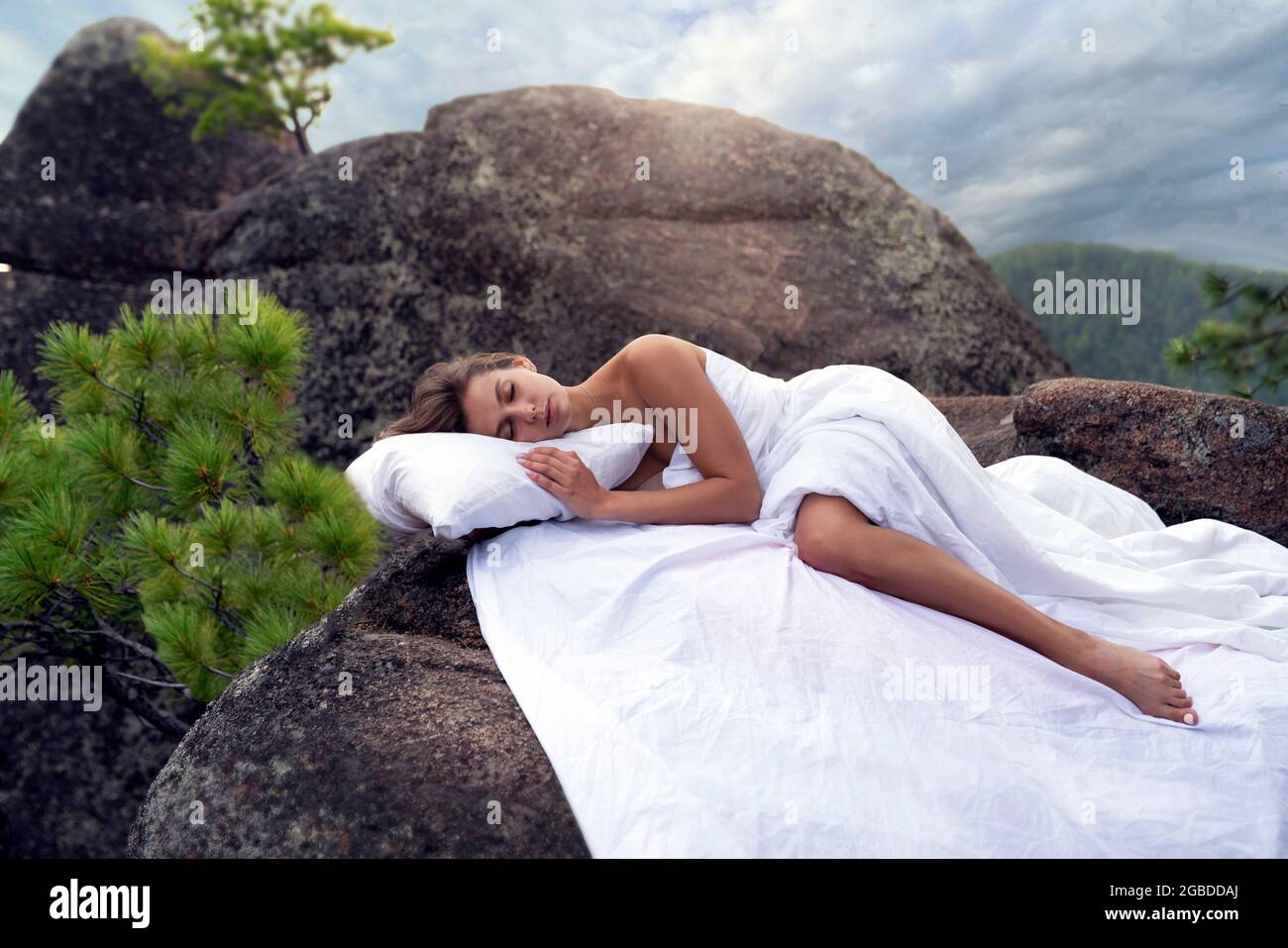 a beautiful young girl is sleeping on the rocks in the mountains, a ...