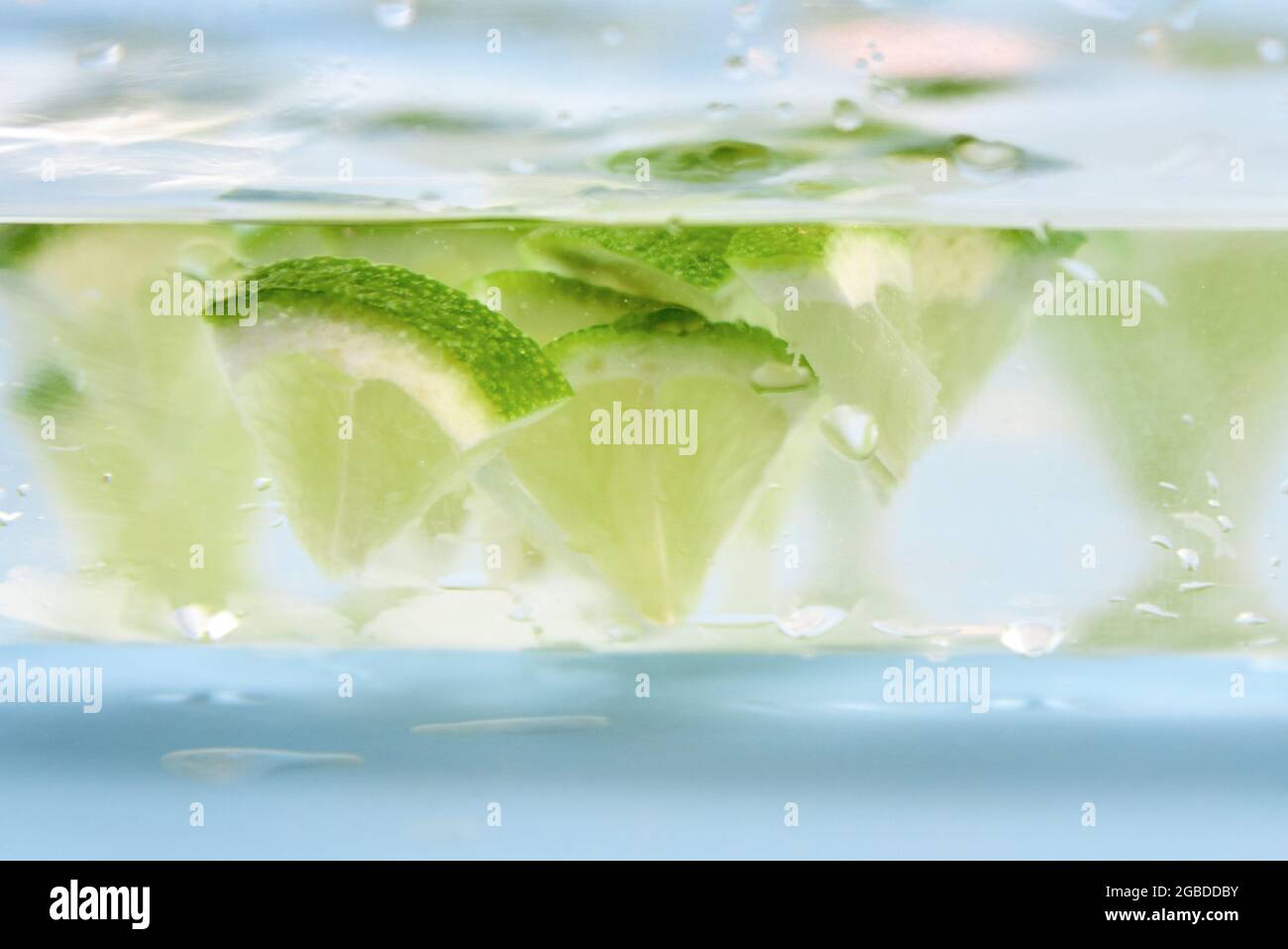 Pieces of lime float in a glass of water, close-up, backdrop Stock ...