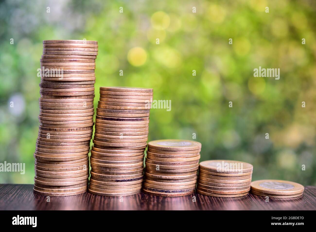 Coin stack graph against green background Stock Photo - Alamy
