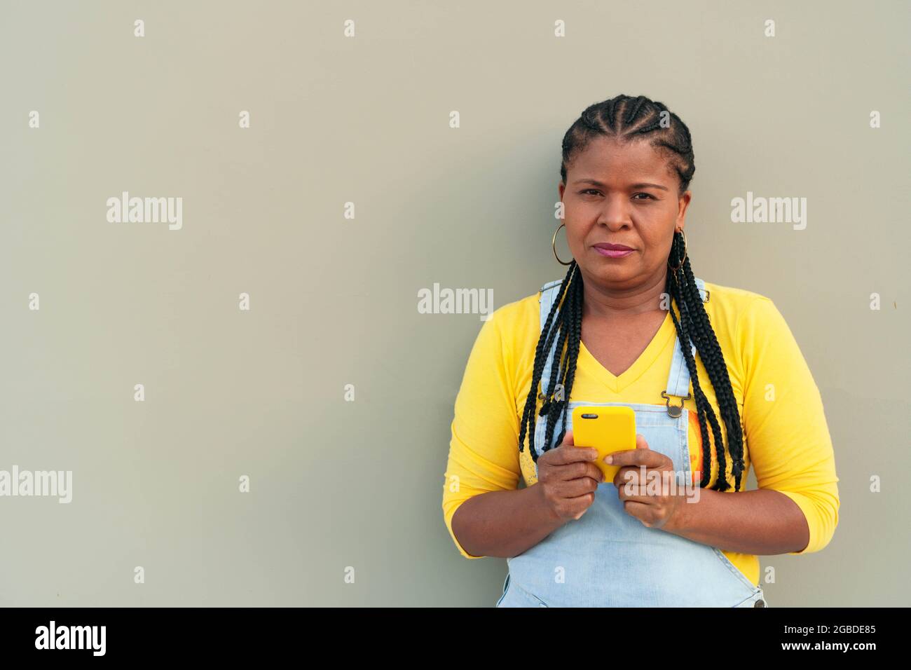 Portrait of a beautiful African woman holding a cell phone leaning ...