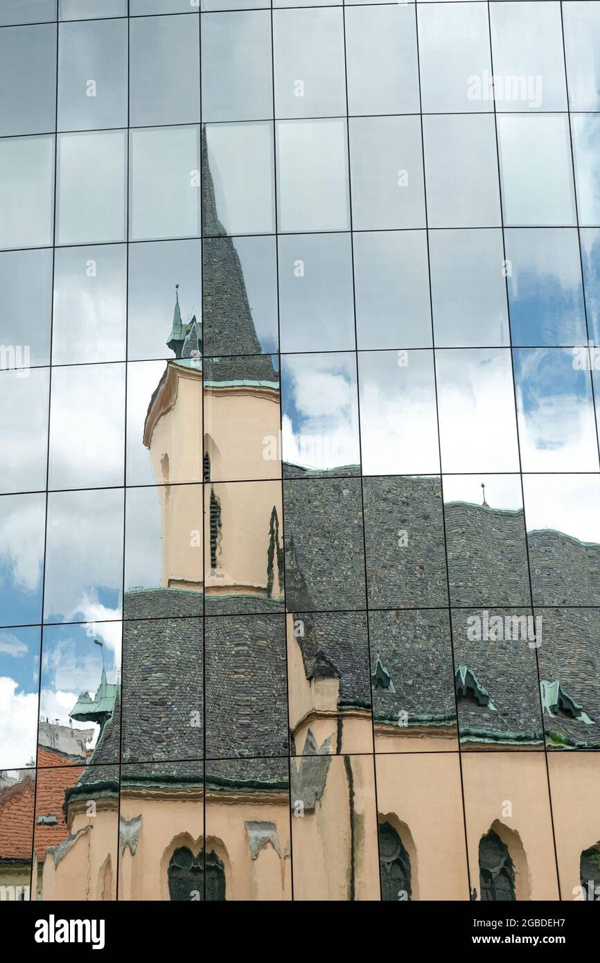 a church reflecting in the mirror glass facade of a modern building ...