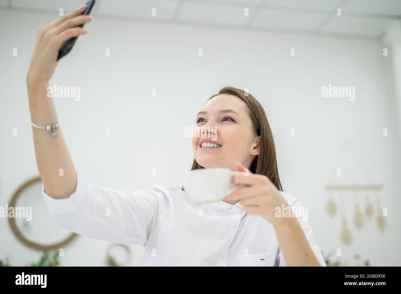 A young brunette blogger drinks coffee in a coffee shop and shoots ...