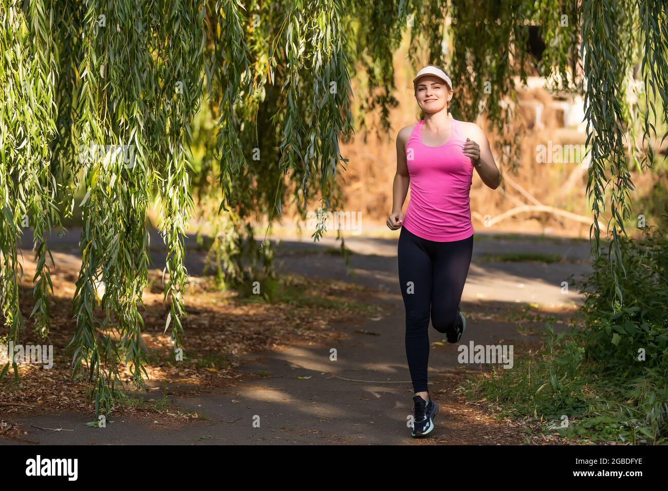 Pretty sporty woman jogging at park Stock Photo - Alamy