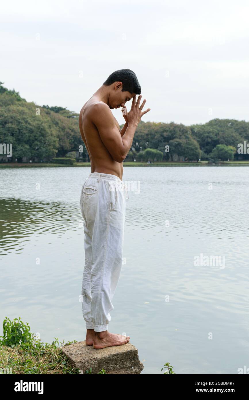 Brazilian young man standing beside a lake in a thankful position Stock ...