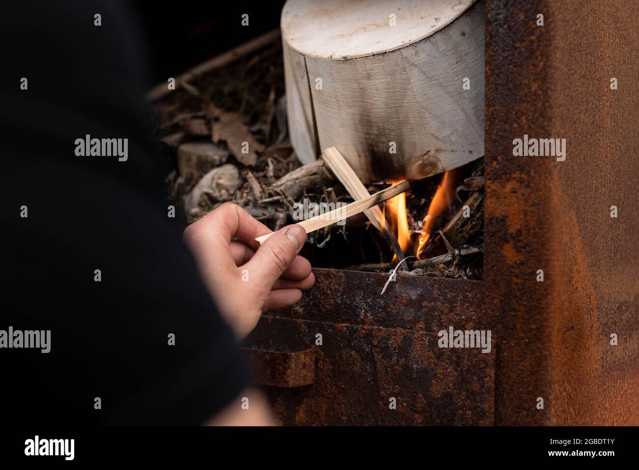 Male hand making a fire with small wooden branches and an old wooden ...