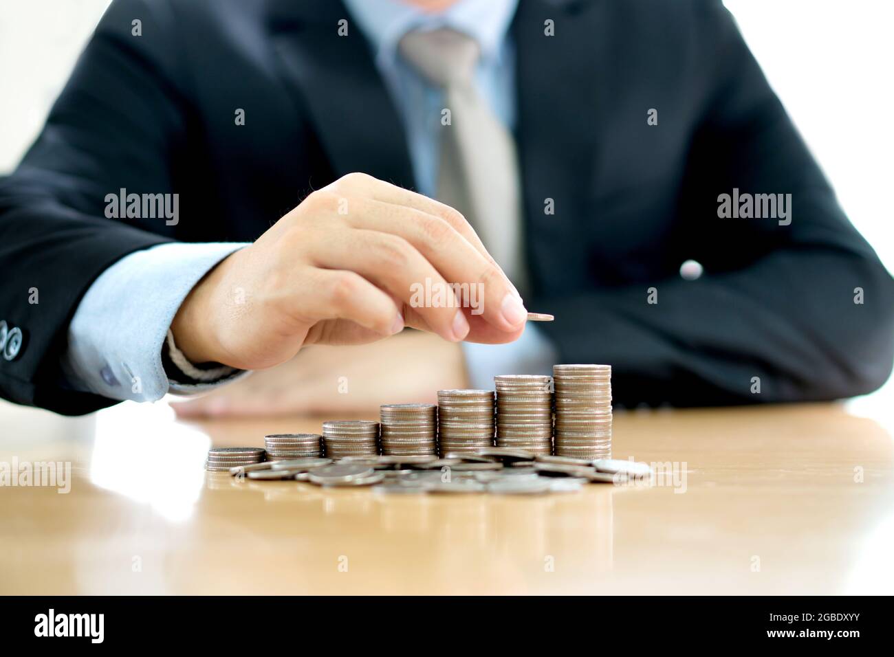 Hand putting stack of coins Stock Photo - Alamy