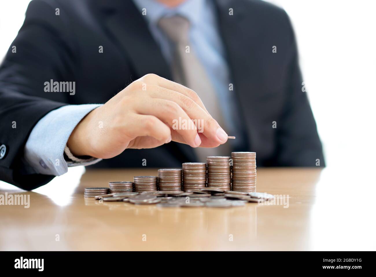 Hand putting stack of coins Stock Photo - Alamy