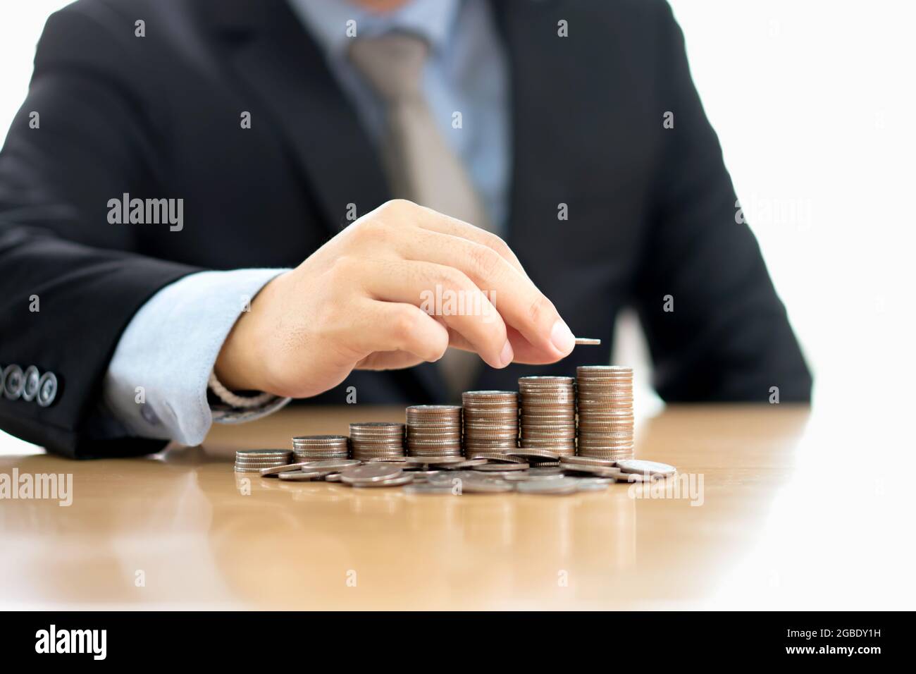 Hand putting stack of coins Stock Photo - Alamy