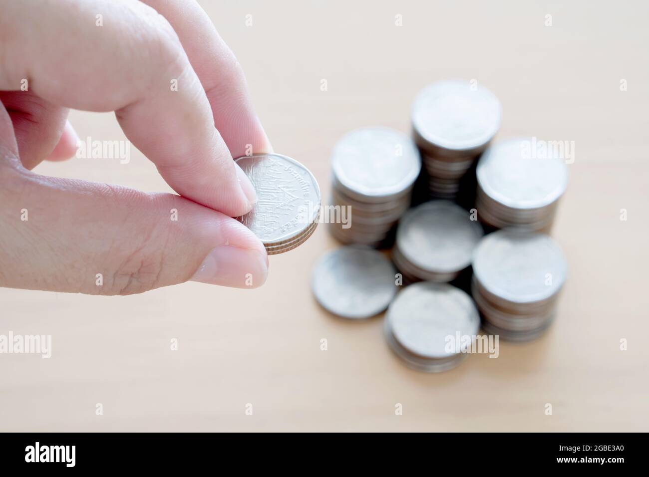 Hand giving coins into stack Stock Photo - Alamy