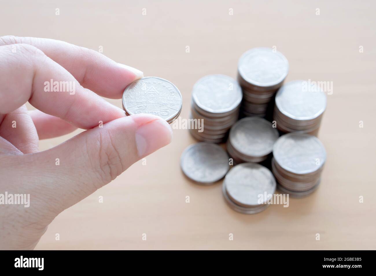 Hand giving coins into stack Stock Photo - Alamy