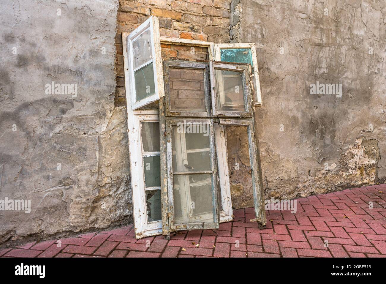 Vertical shot of old, broken window and door leaning on a rusty wall in ...