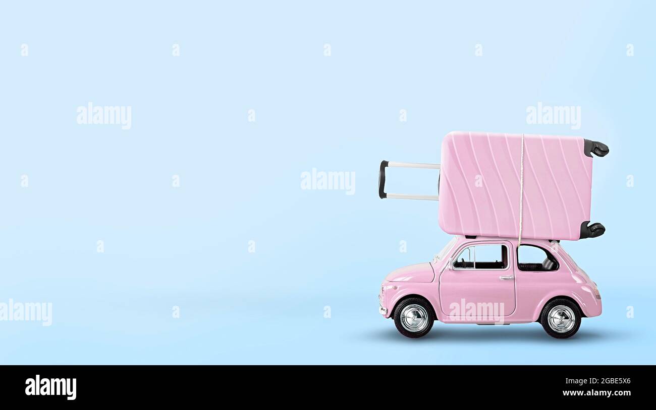 Pink toy car with pink suitcase on a roof on a light blue background ...