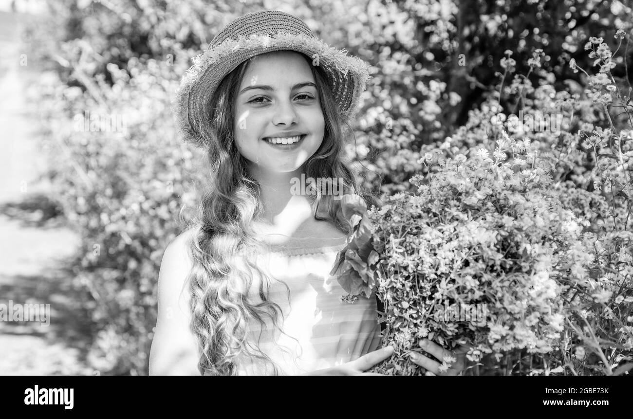 Happy small girl with sun hat on long hair smile with flowers on sunny ...