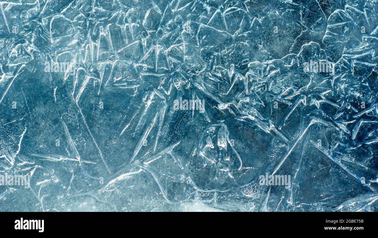 Beautiful ice texture with cracks of a frozen puddle on the asphalt for ...