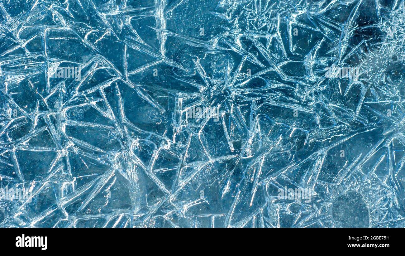Beautiful ice texture with cracks of a frozen puddle on the asphalt for ...