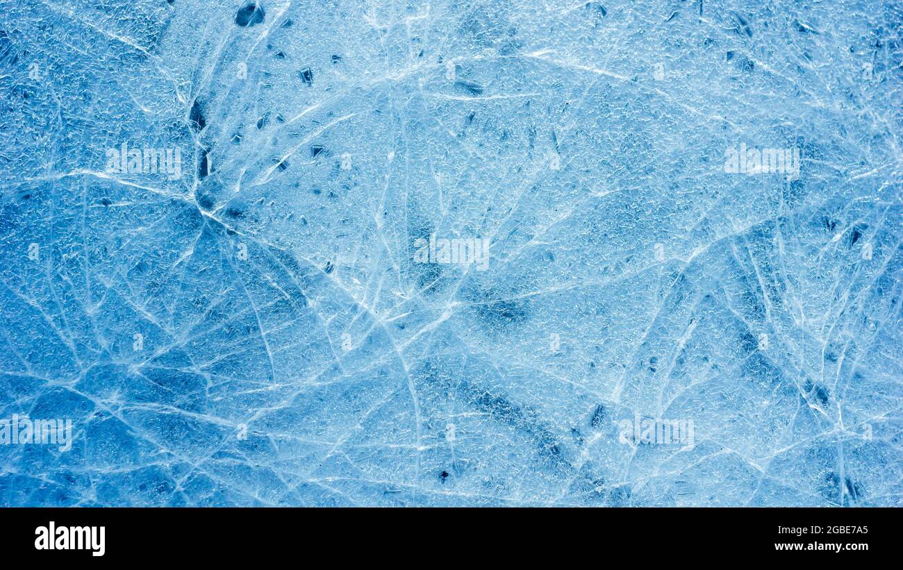 Beautiful ice texture with cracks of a frozen puddle on the asphalt for ...