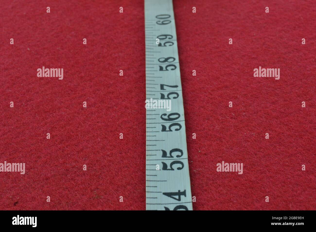 White tape measure on a red background with the numbers Stock Photo - Alamy