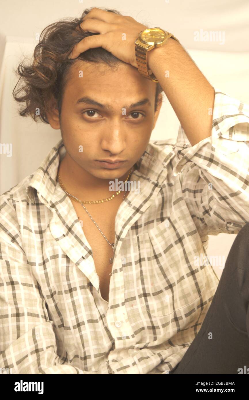 Vertical shot of an Indian young male sitting with a sad melancholic ...