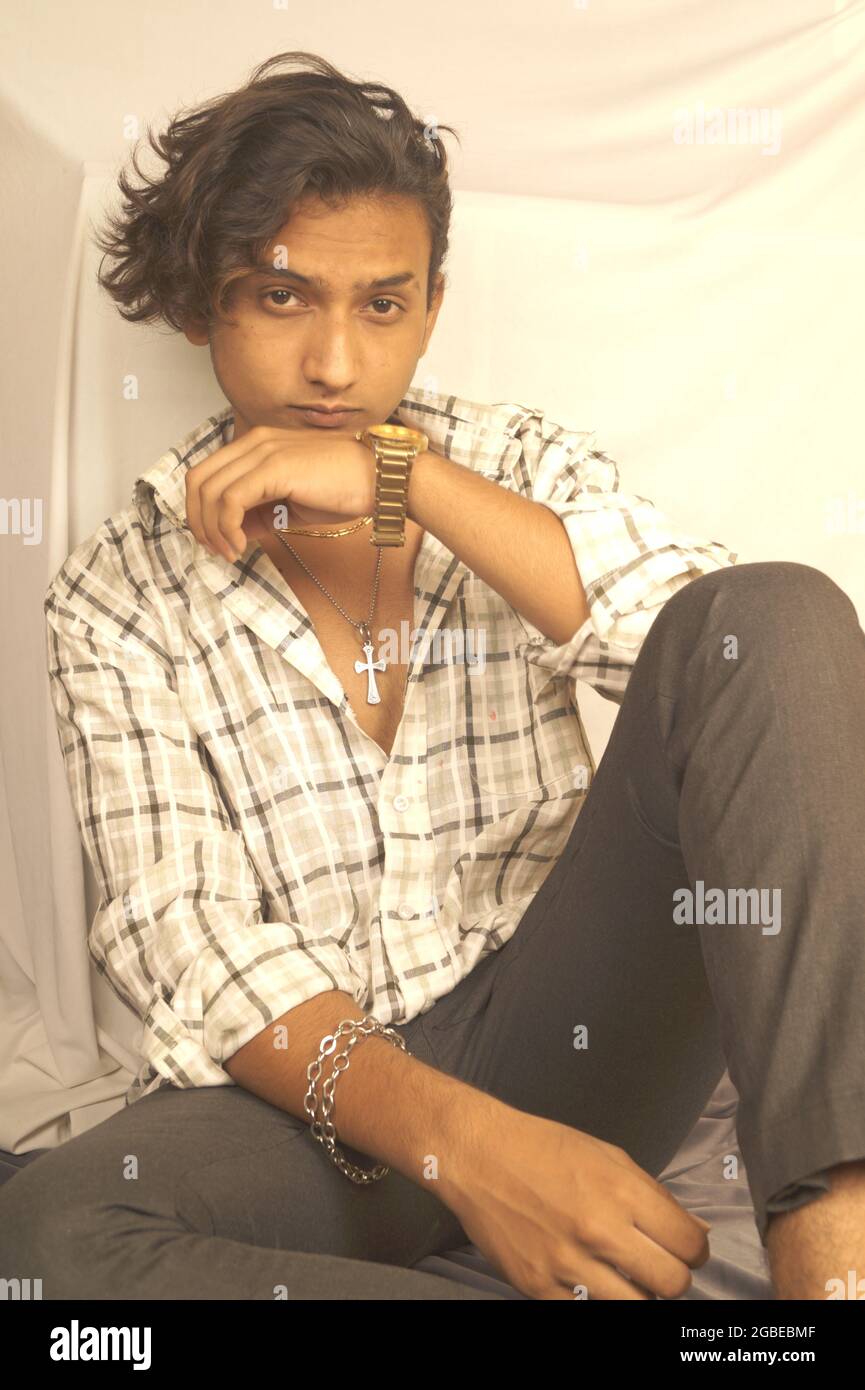Vertical shot of an Indian young male sitting with a sad melancholic ...