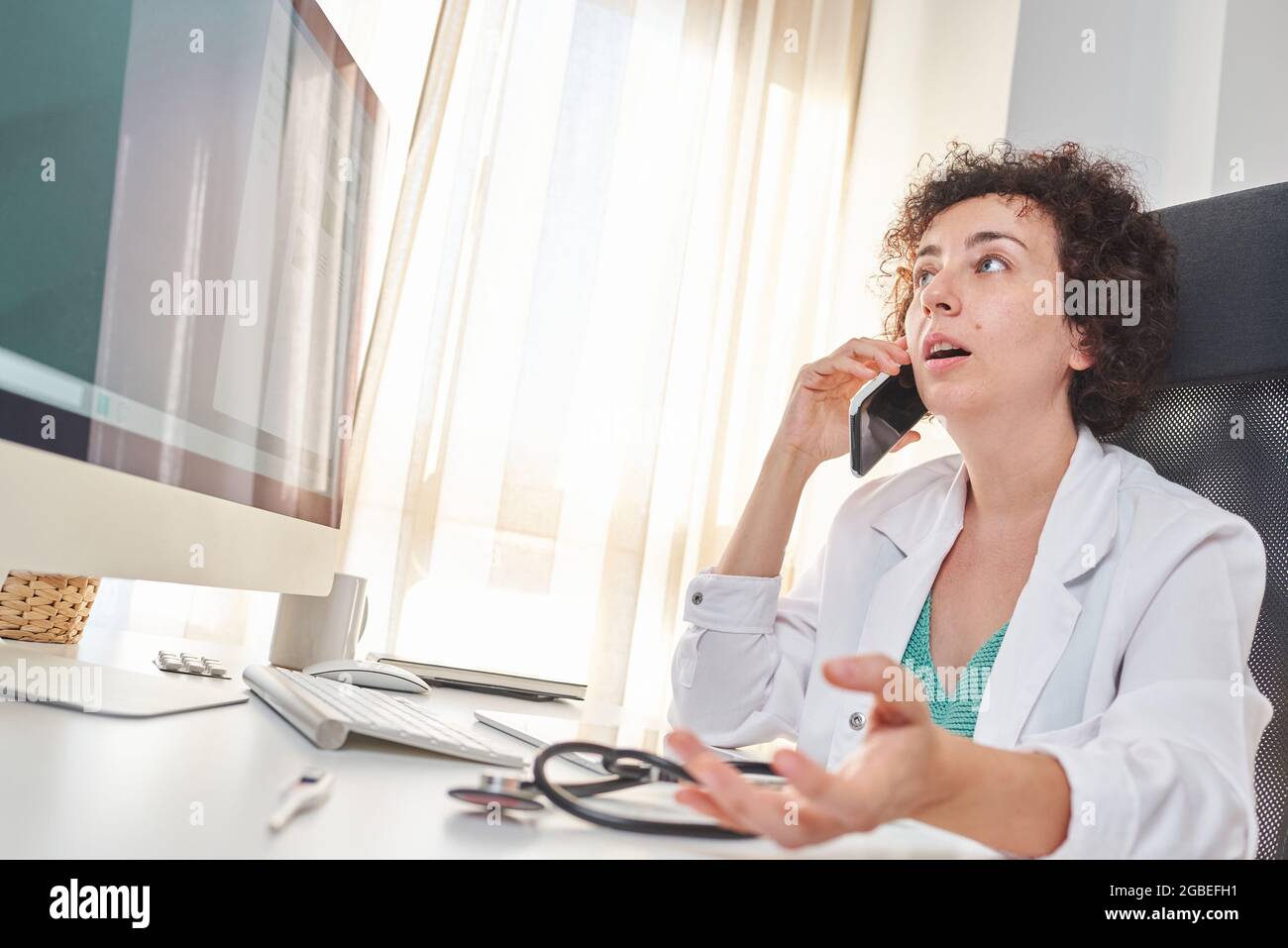 A female doctor answers a phone call from her office Stock Photo - Alamy