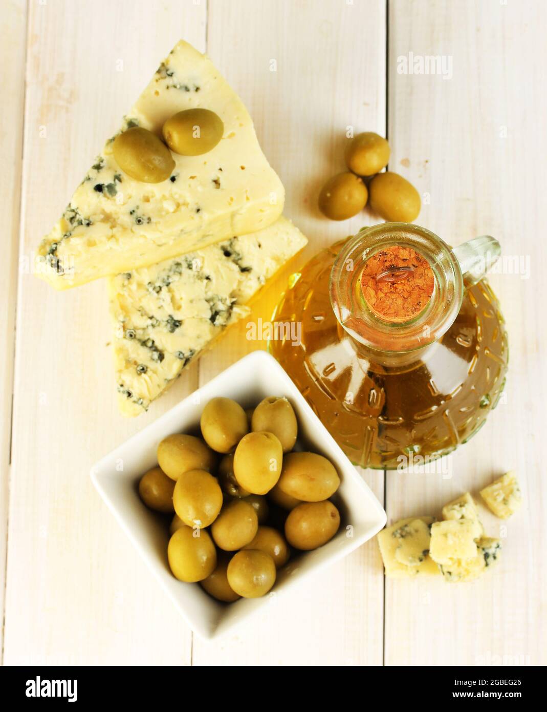 Cheese with mold and decanter of olive oil on white wooden background ...