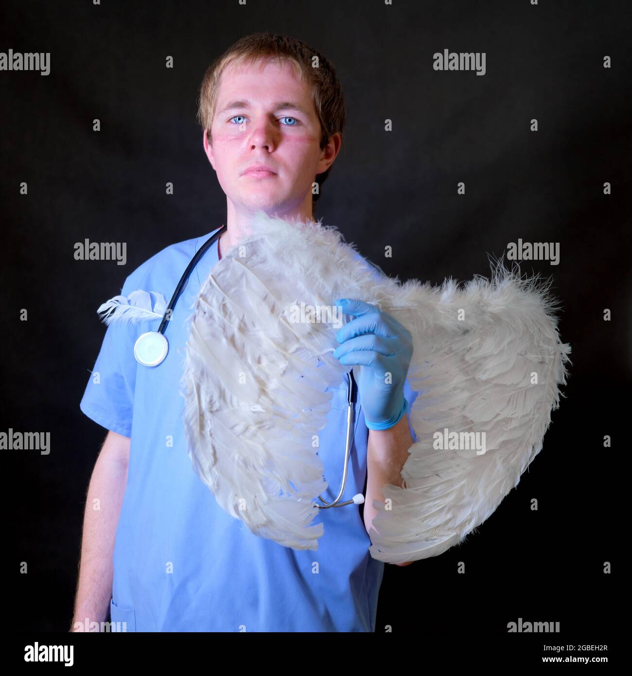 Young doctor removes white angel wings on black background Stock Photo ...