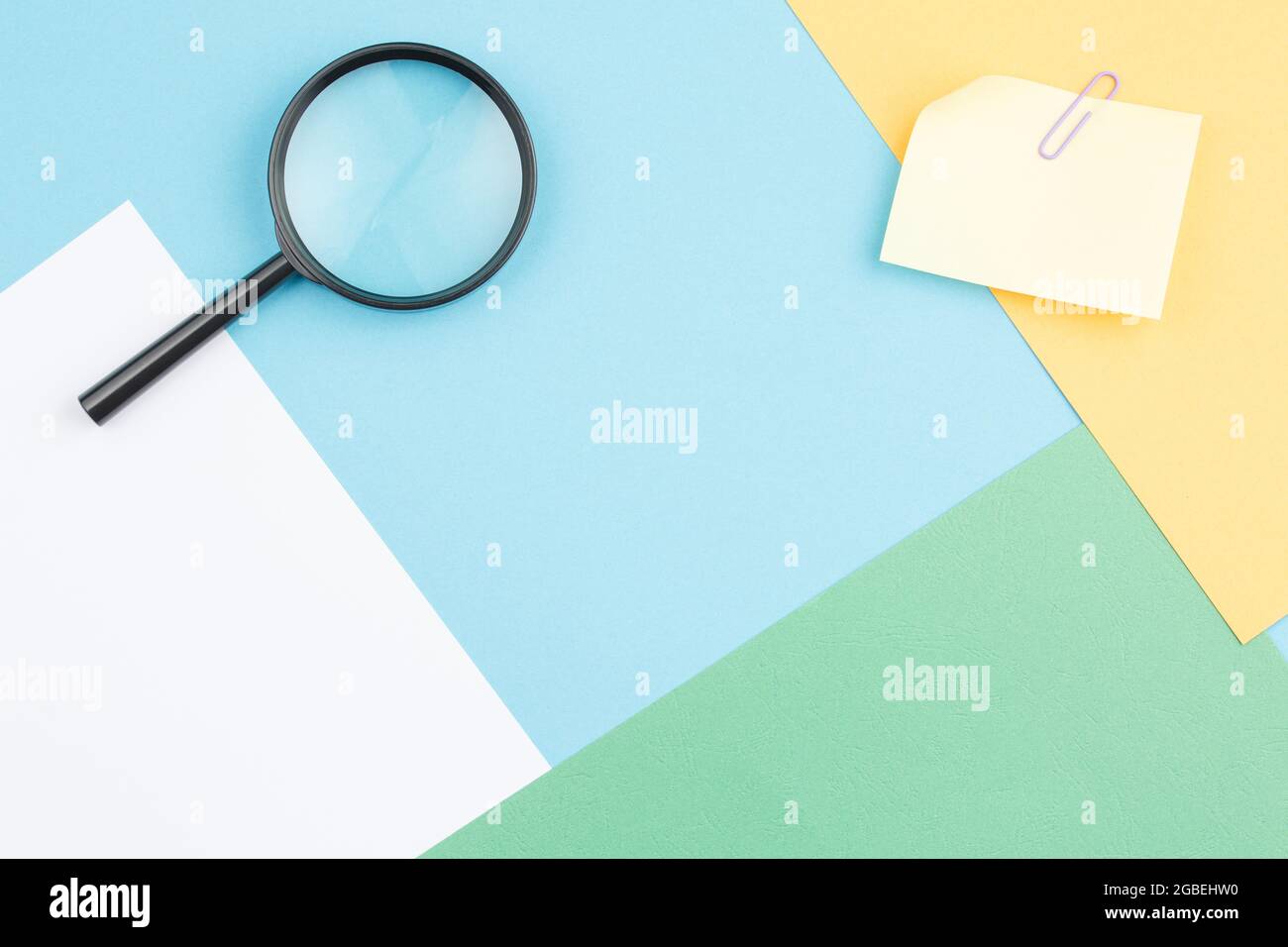 Colored paper background with magnifying glass Stock Photo - Alamy