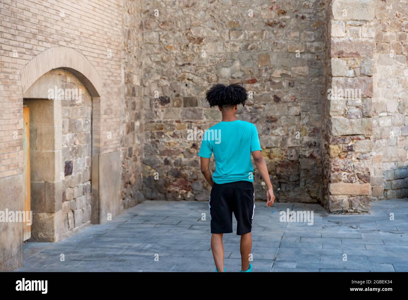 Afro latin young man walking backwards in the street Stock Photo - Alamy