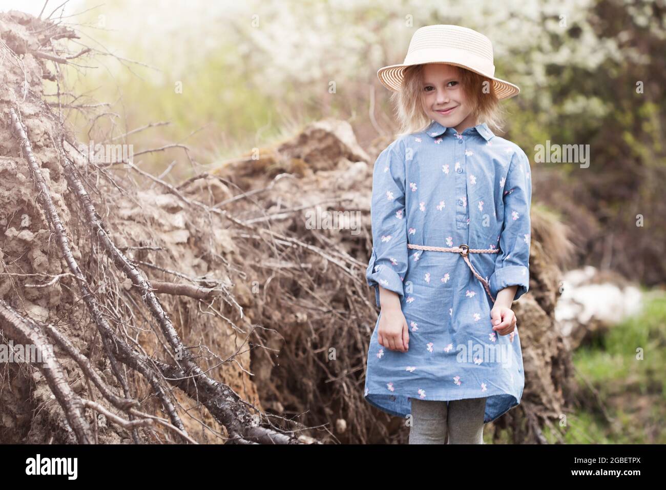 Cute little caucasian girl standing next to a fallen tree with upturned ...