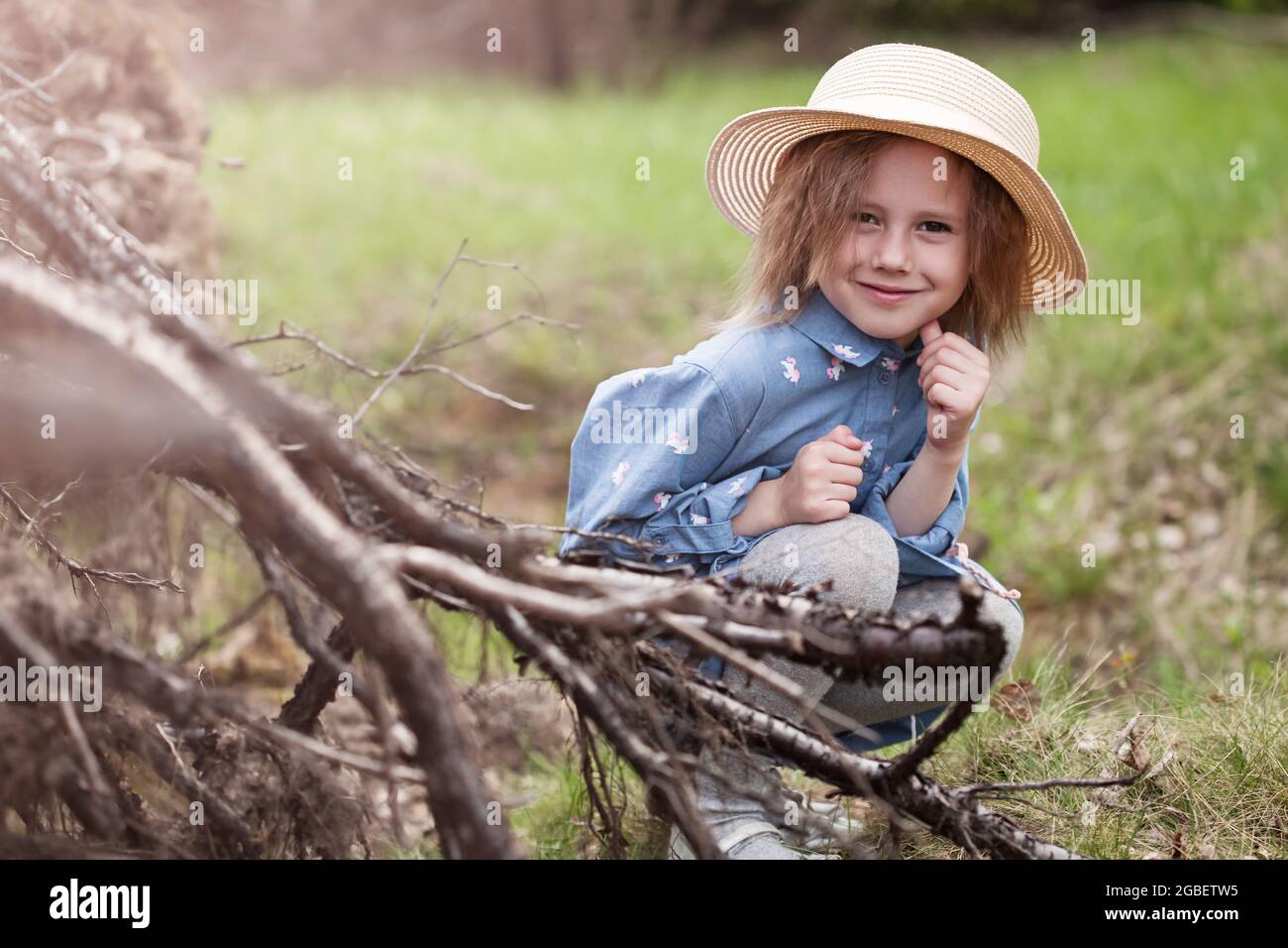 Cute small caucasian girl sits next to a fallen tree with upturned ...