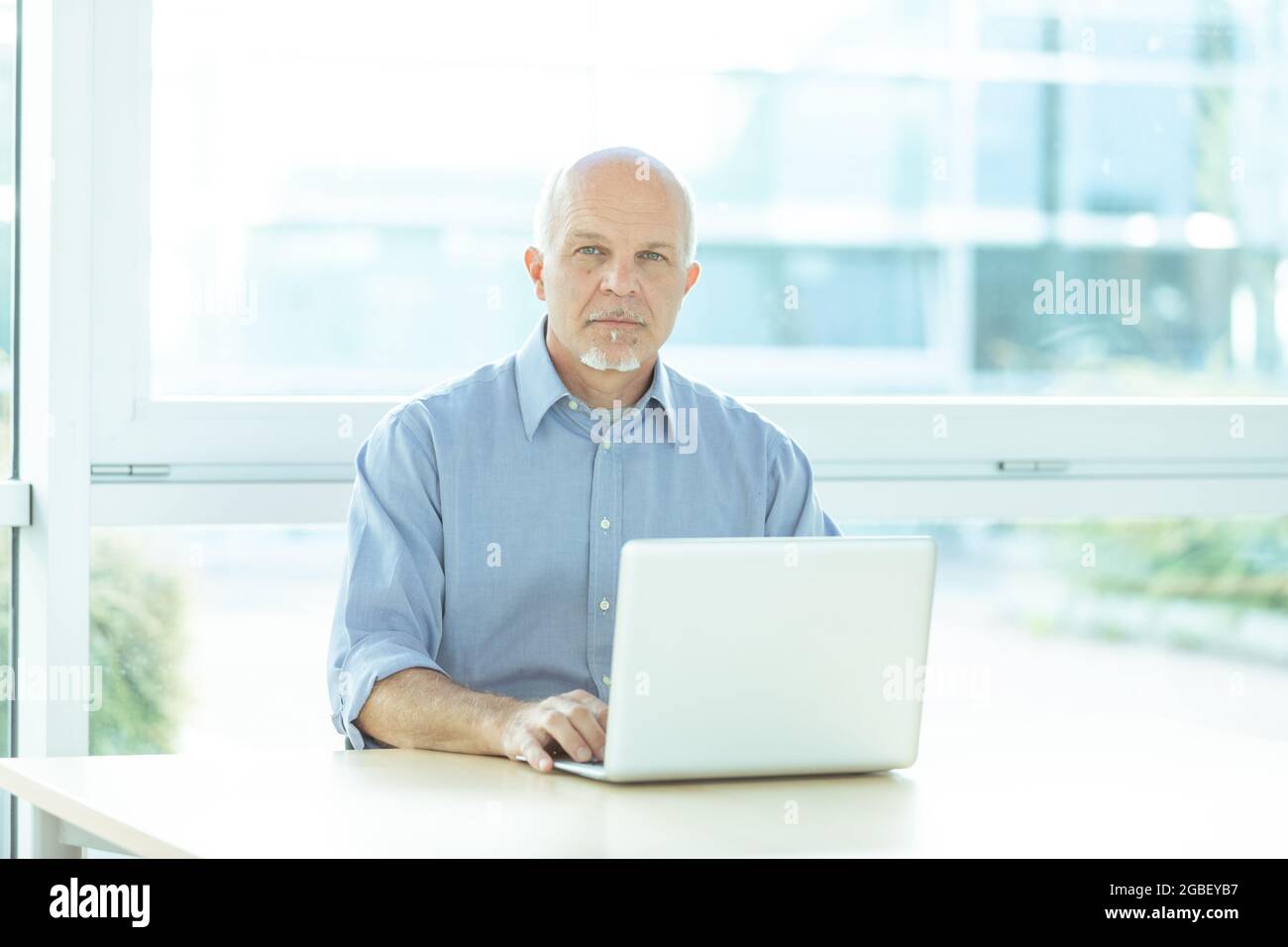 Thoughtful businessman sitting working at his laptop computer in a ...