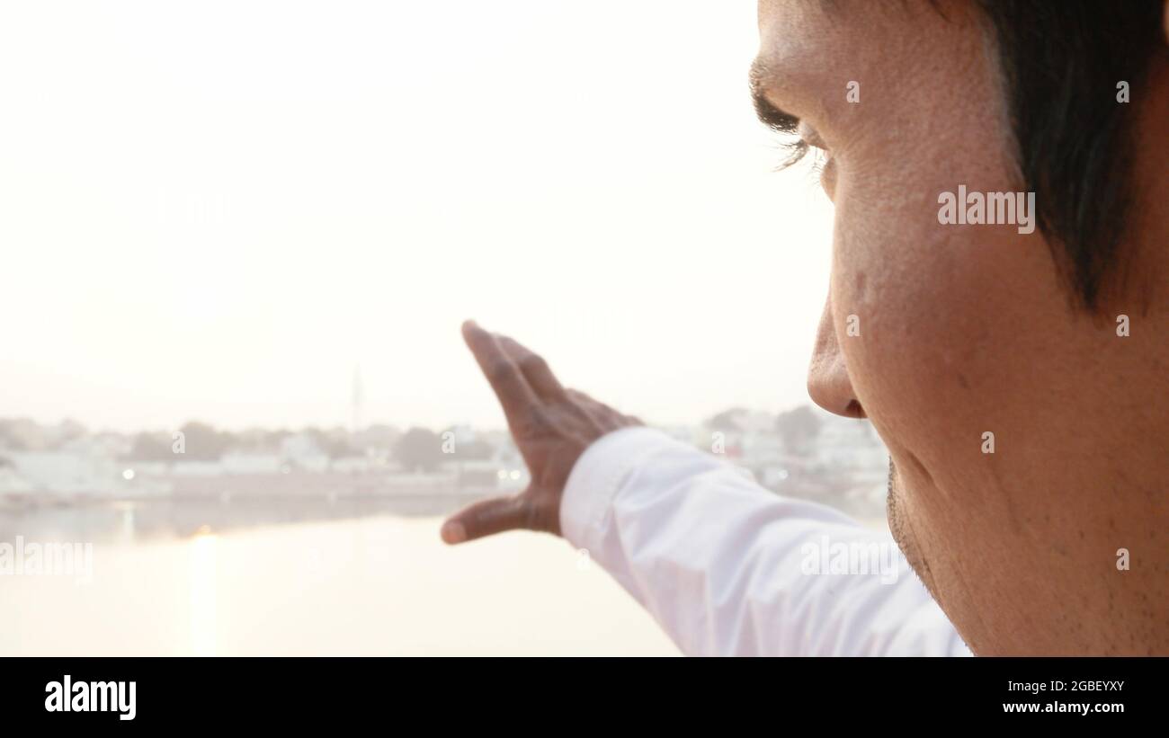 Indian man pointing to the lake during the sunset Stock Photo - Alamy