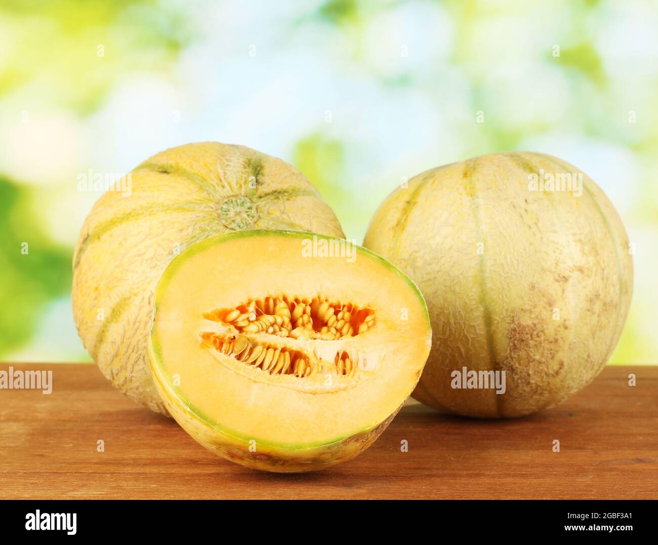 Cut melon on wooden table on green background Stock Photo - Alamy