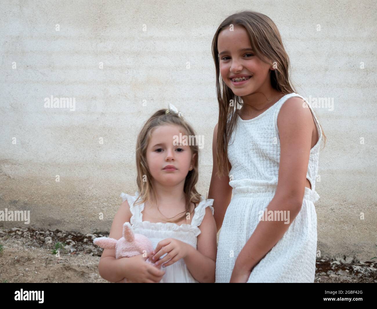 Adorable Spanish girls wearing white dresses are posing outdoors Stock ...