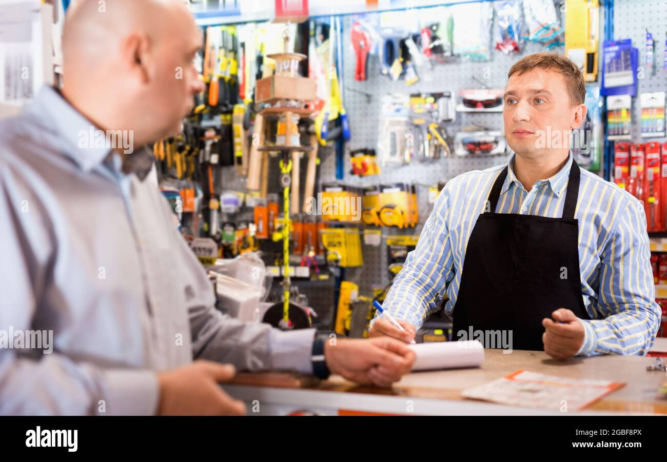 Adult salesman offering tools to man Stock Photo - Alamy