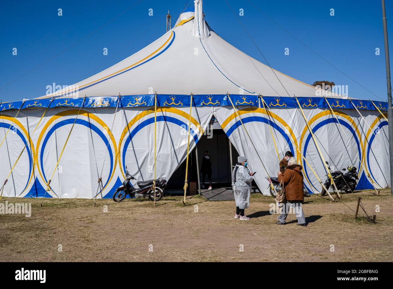 A health worker Personal Protective Equipment greets people arriving at ...