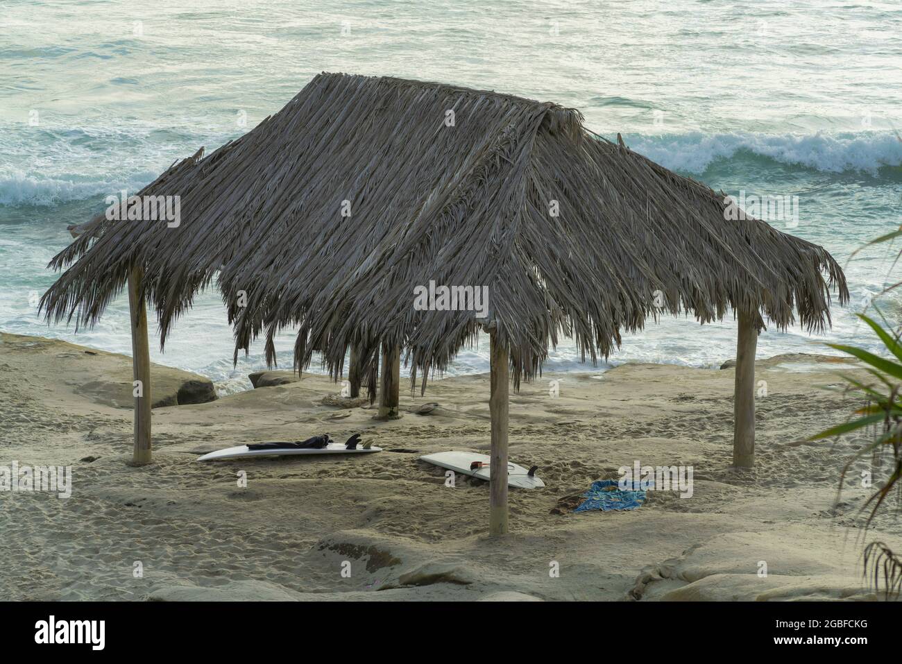 Beautiful view of an ocean and straw hut on a sandy beach with surfing ...