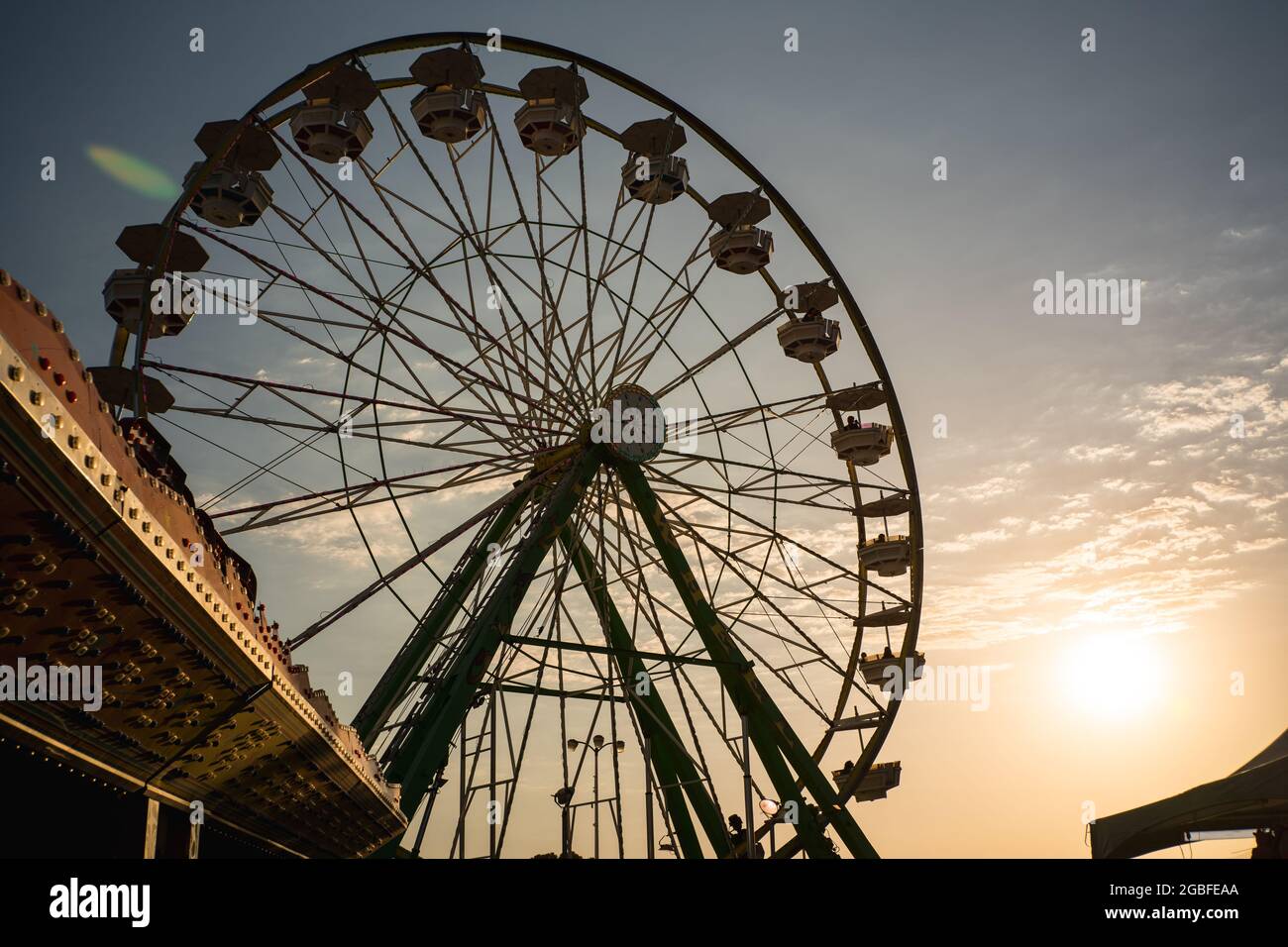 Shot of spinning Ferris wheel attraction on the background of sunset ...
