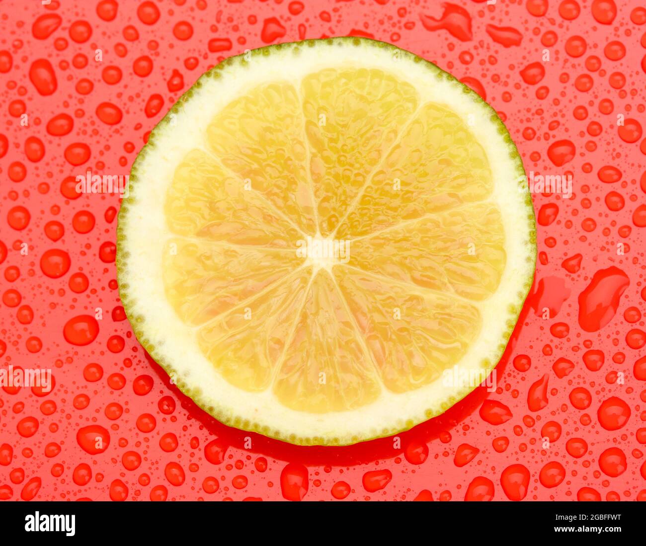 Slice of lime with drop on red background Stock Photo - Alamy