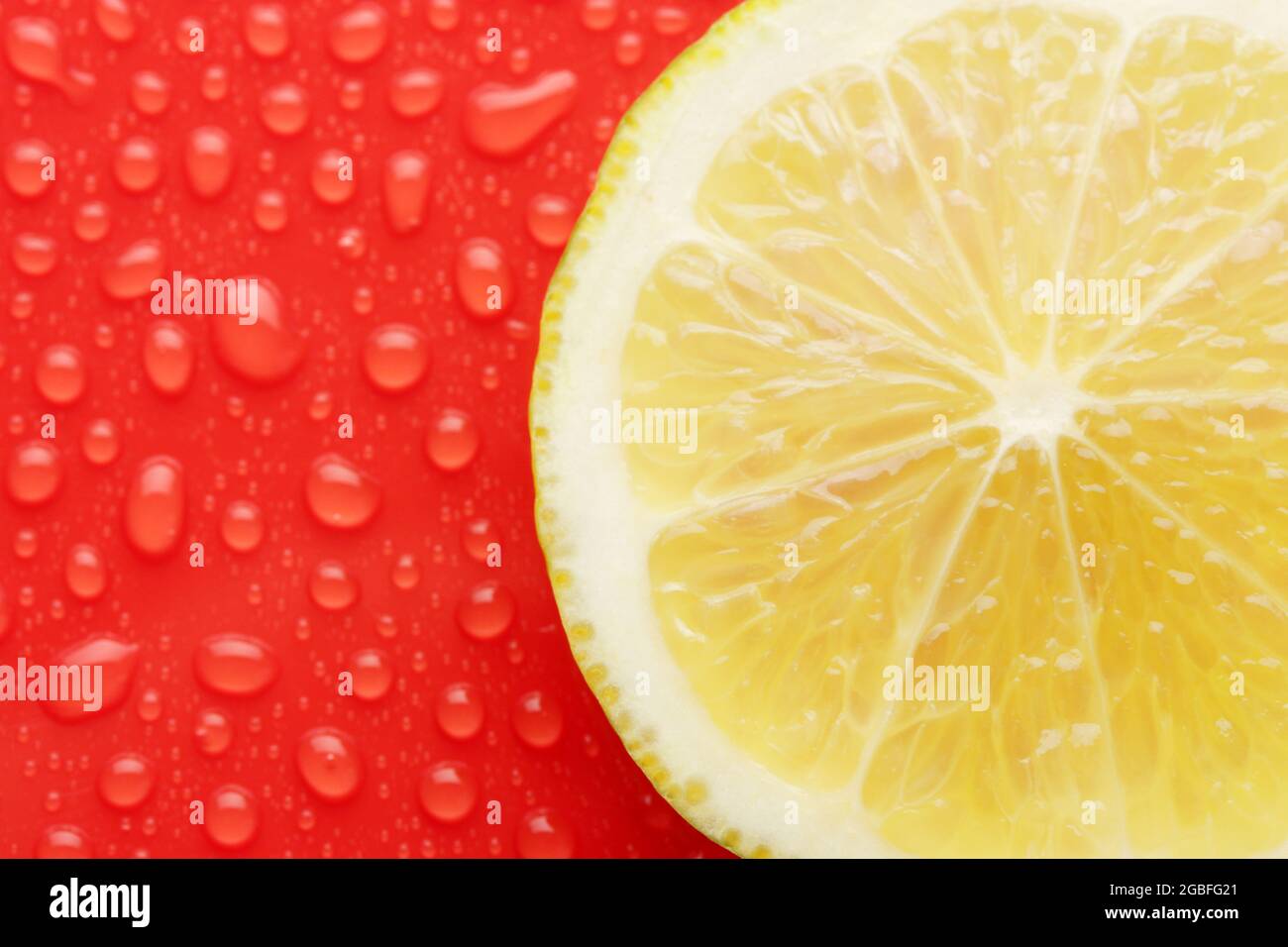 Slice of lemon with drop on red background Stock Photo - Alamy