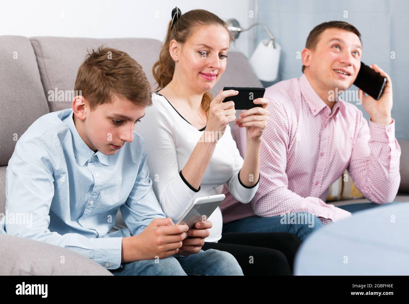 Parents and son using phones Stock Photo - Alamy
