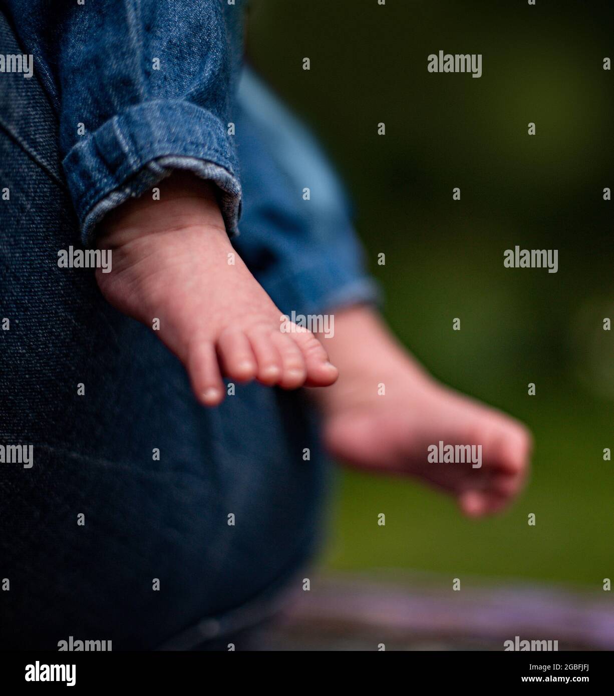 Baby feet hanging down with a blurred background Stock Photo - Alamy