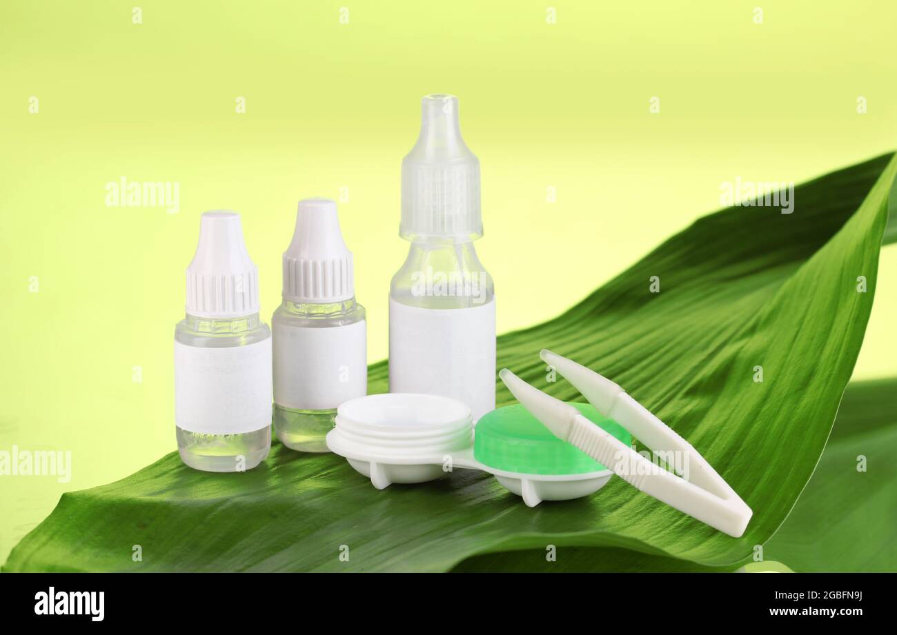 Eye drops and lenses on leaf on green background Stock Photo - Alamy