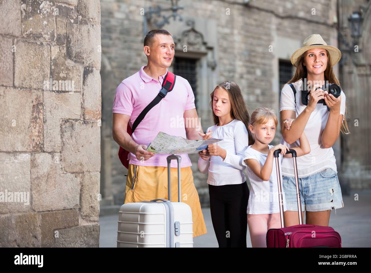 Young parents tourists with kids using map and camera Stock Photo - Alamy