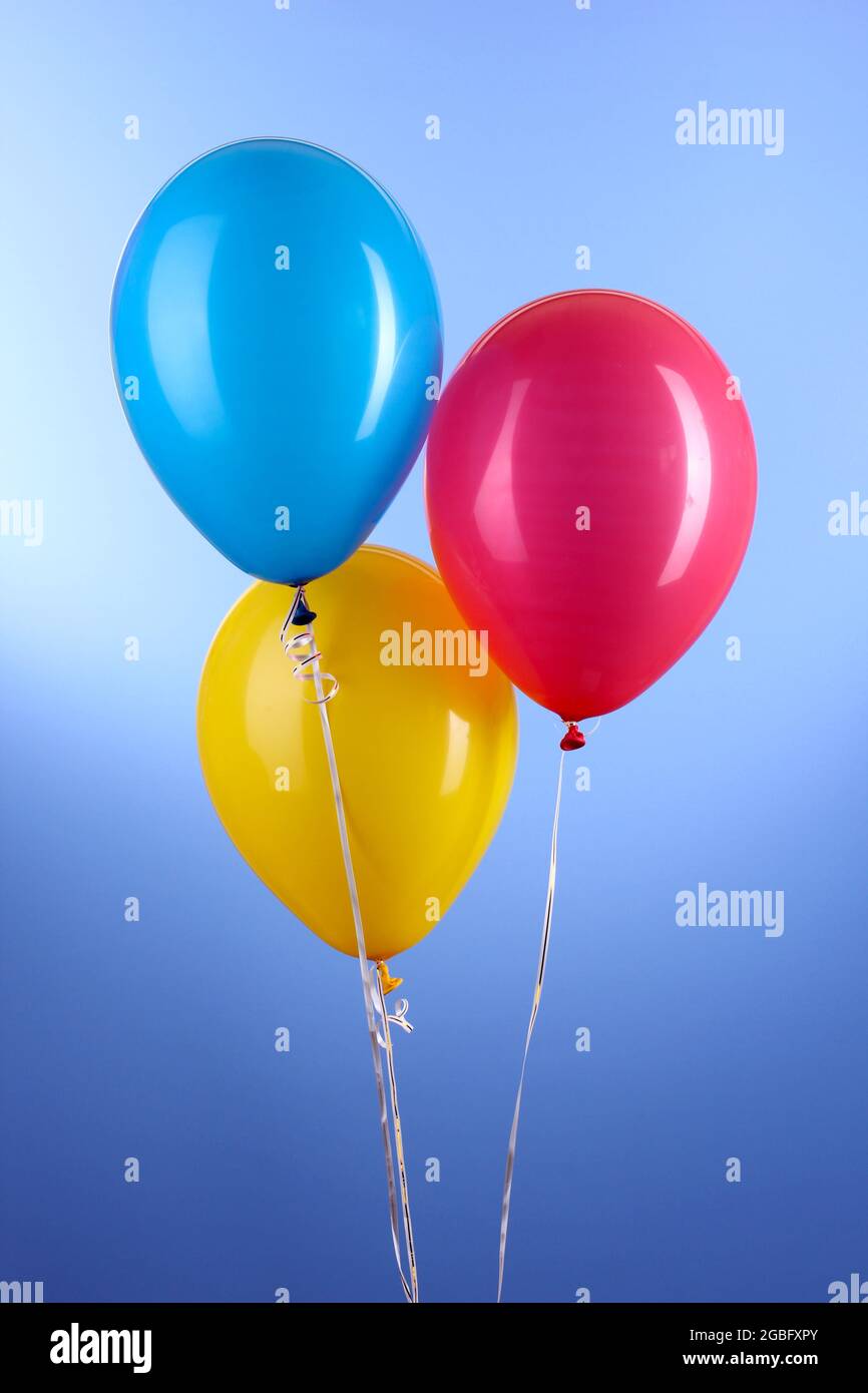 Three colorful balloons on blue background Stock Photo - Alamy
