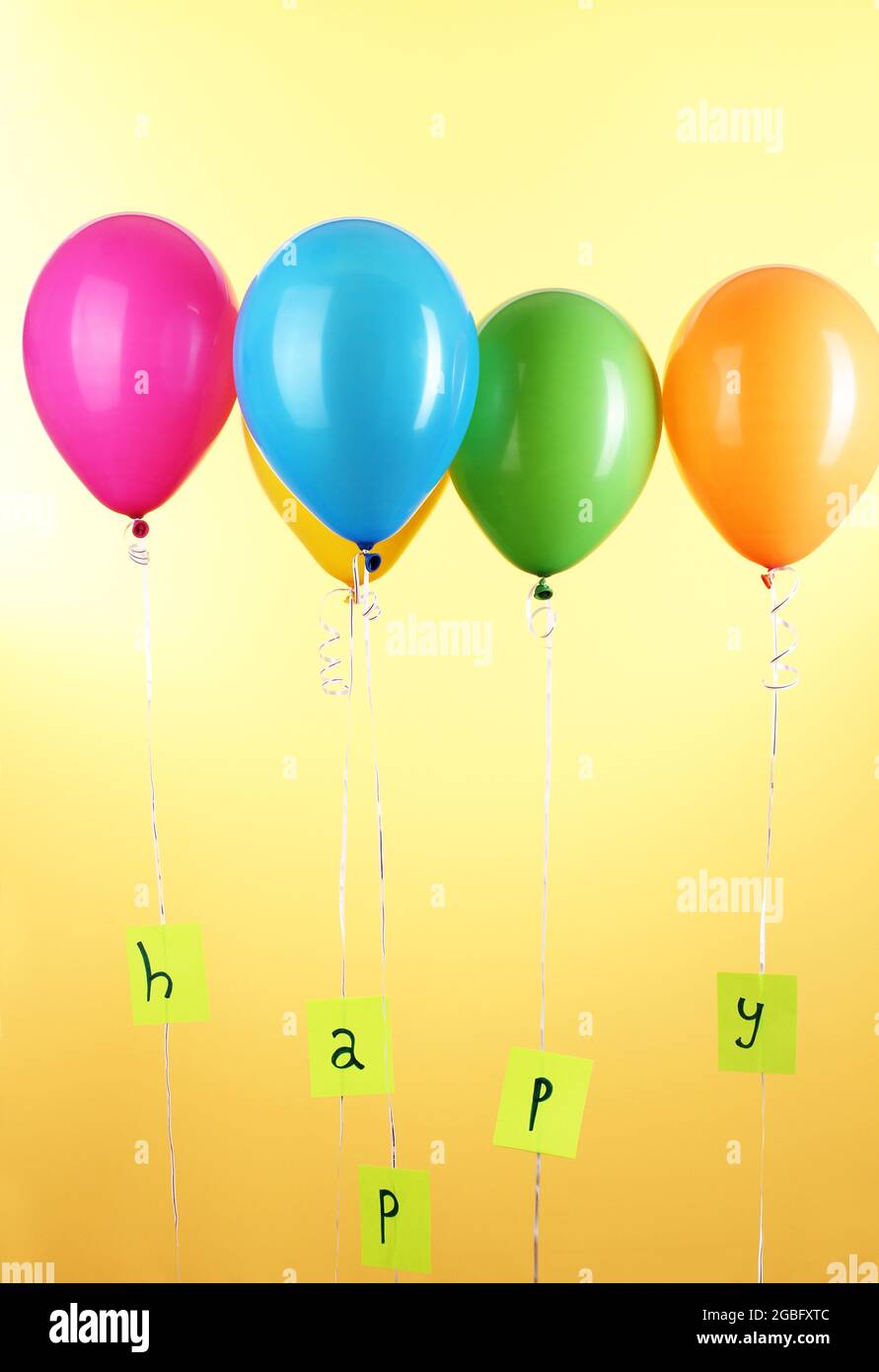 Colorful balloons keeps word happy on yellow background Stock Photo - Alamy