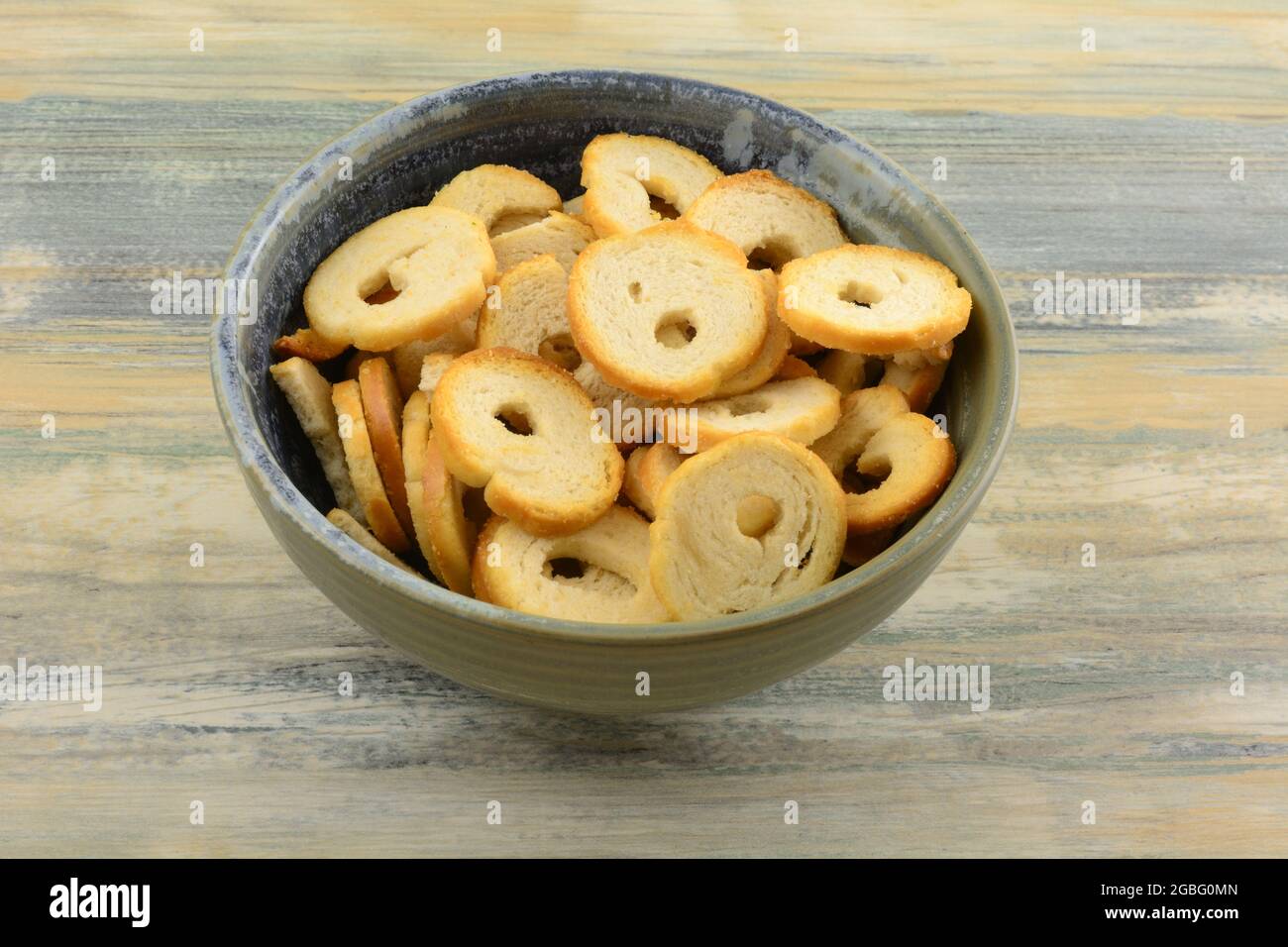 Roasted garlic bread chips in ceramic snack bowl on table Stock Photo ...